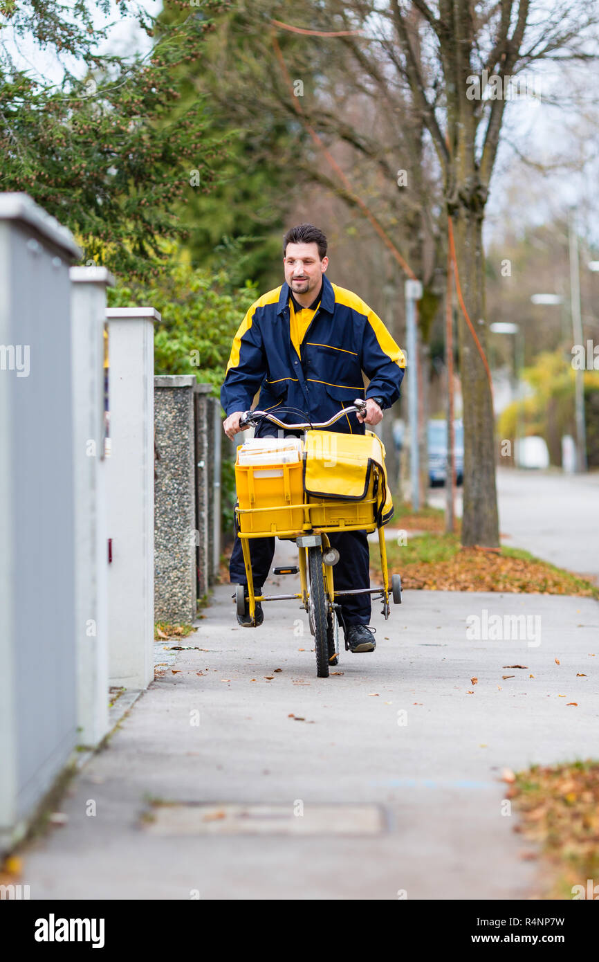 Postman riding his cargo bike carrying out mail Stock Photo - Alamy
