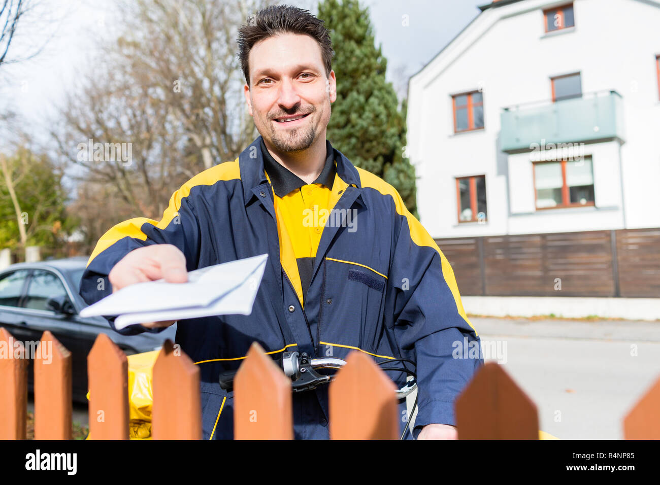 Mailman passing letters to addressee over fence Stock Photo - Alamy