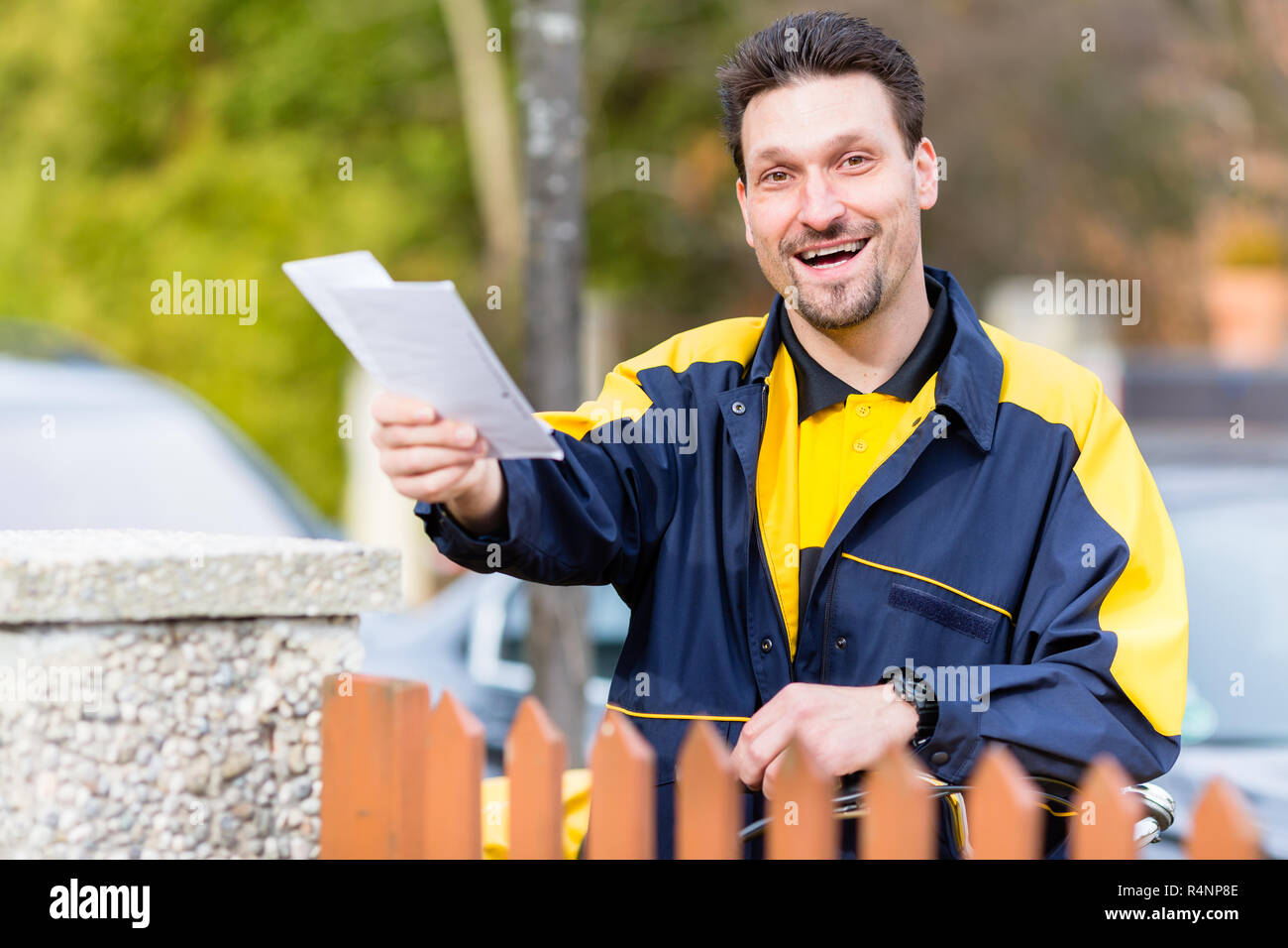 Postman delivering letters to mailbox of recipient Stock Photo - Alamy