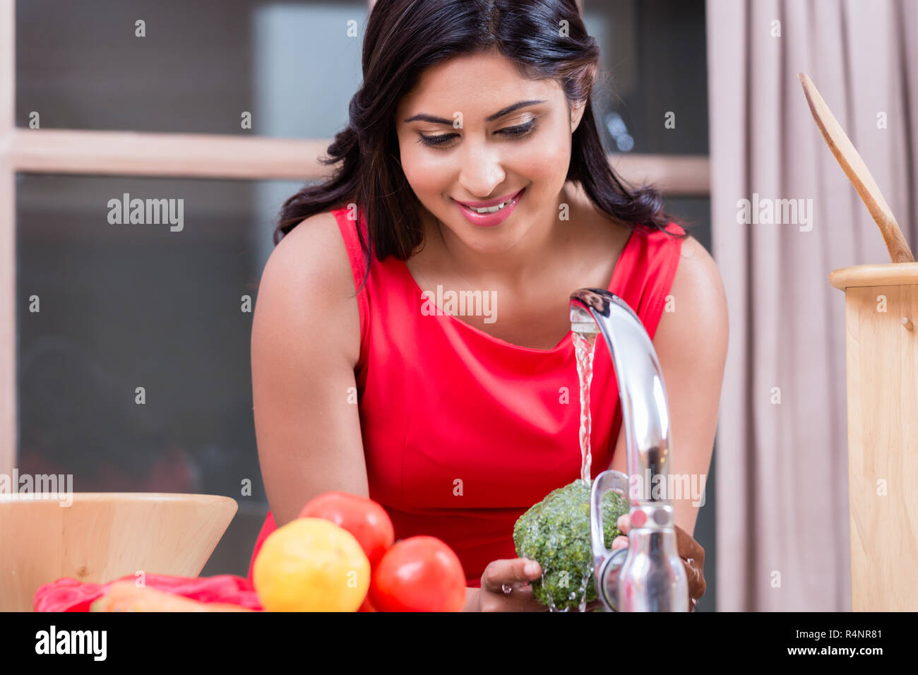 Young woman washing vegetables in the kitchen Stock Photo - Alamy