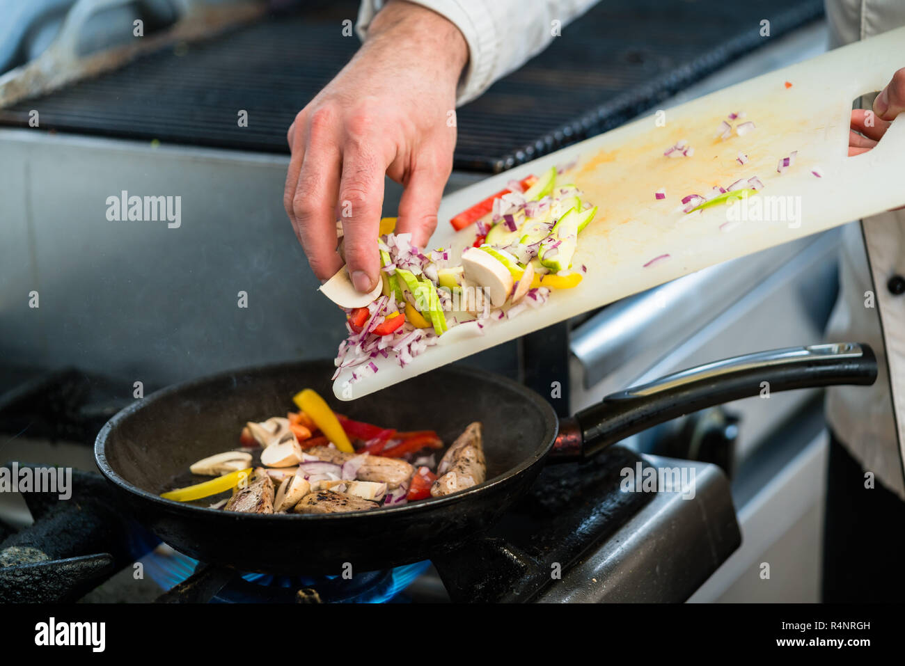 Chef putting ingredients to pan in restaurant kitchen Stock Photo - Alamy
