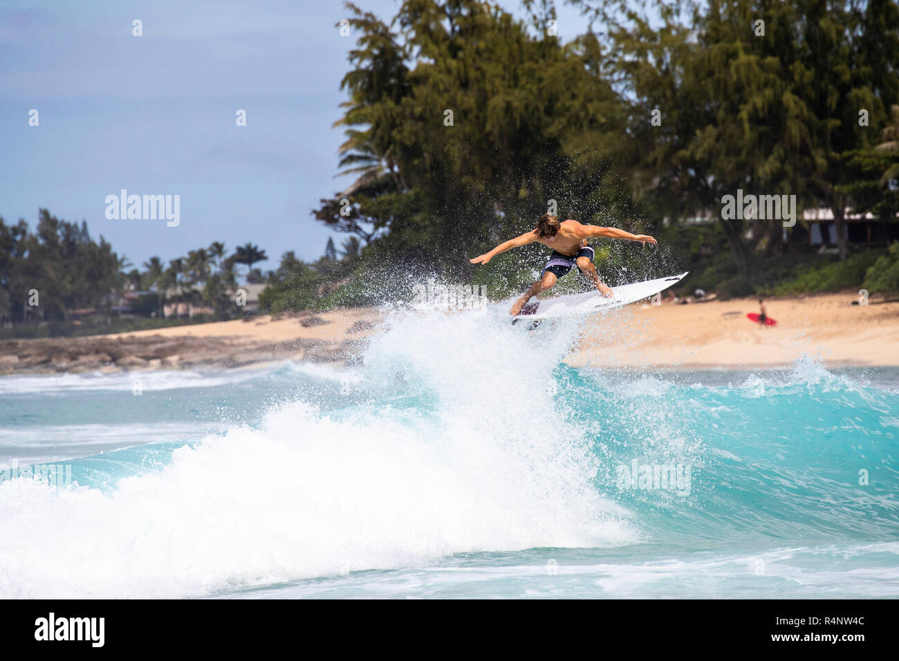 A male surfer gets air off the lip of a wave on the north shore of Oahu ...