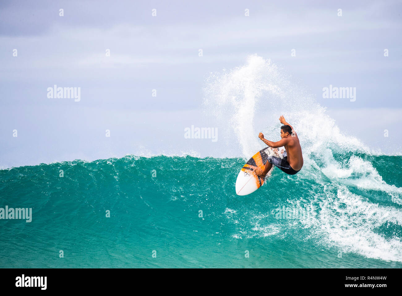 A fit male surfer rips across a wave on the north shore of Oahu, Hawaii ...