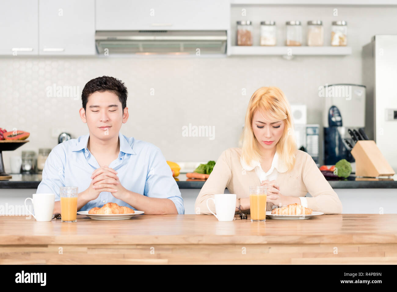 Asian couple praying before having breakfast together Stock Photo - Alamy