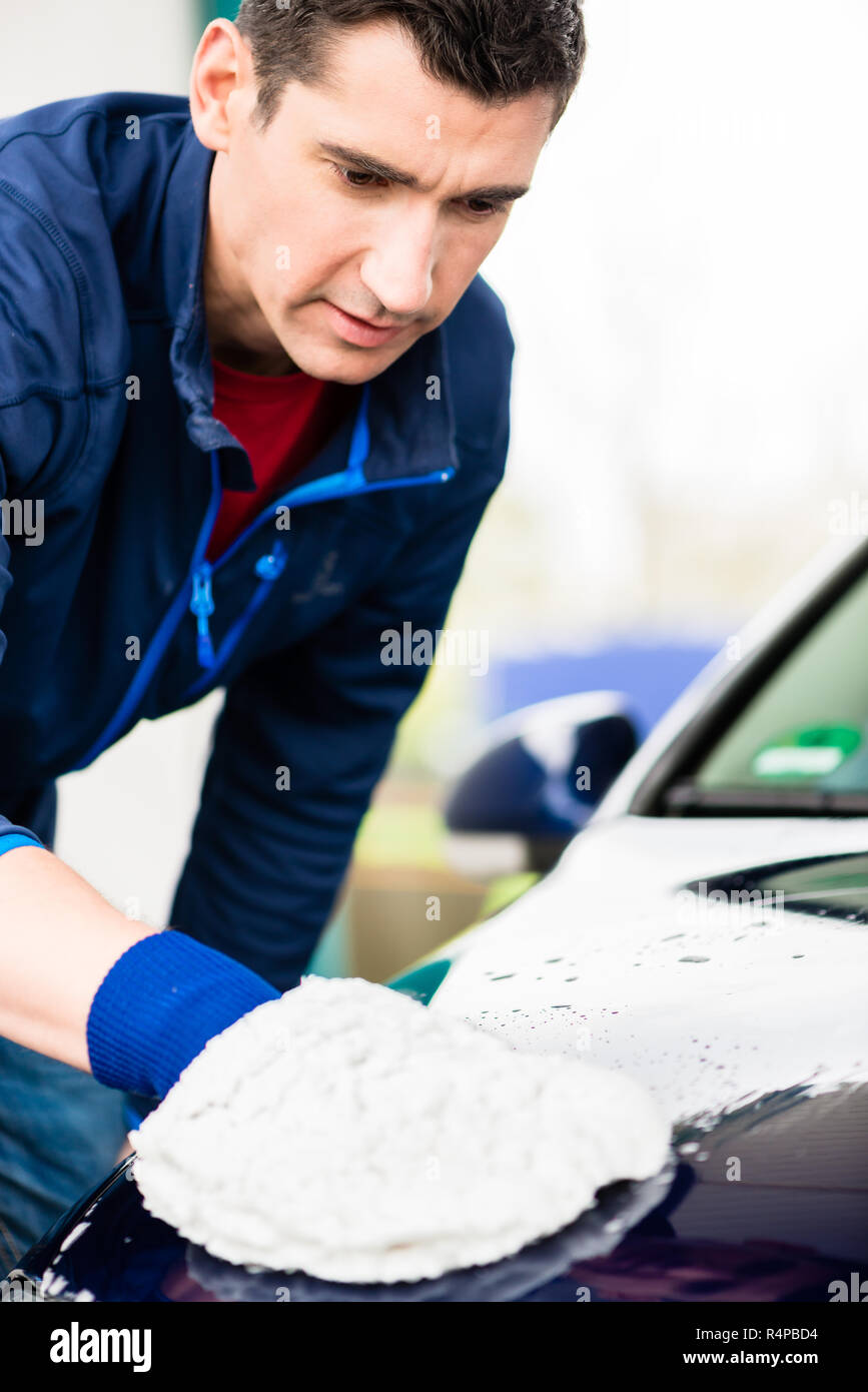 Hard-working man polishing car with white microfiber mitt Stock Photo ...