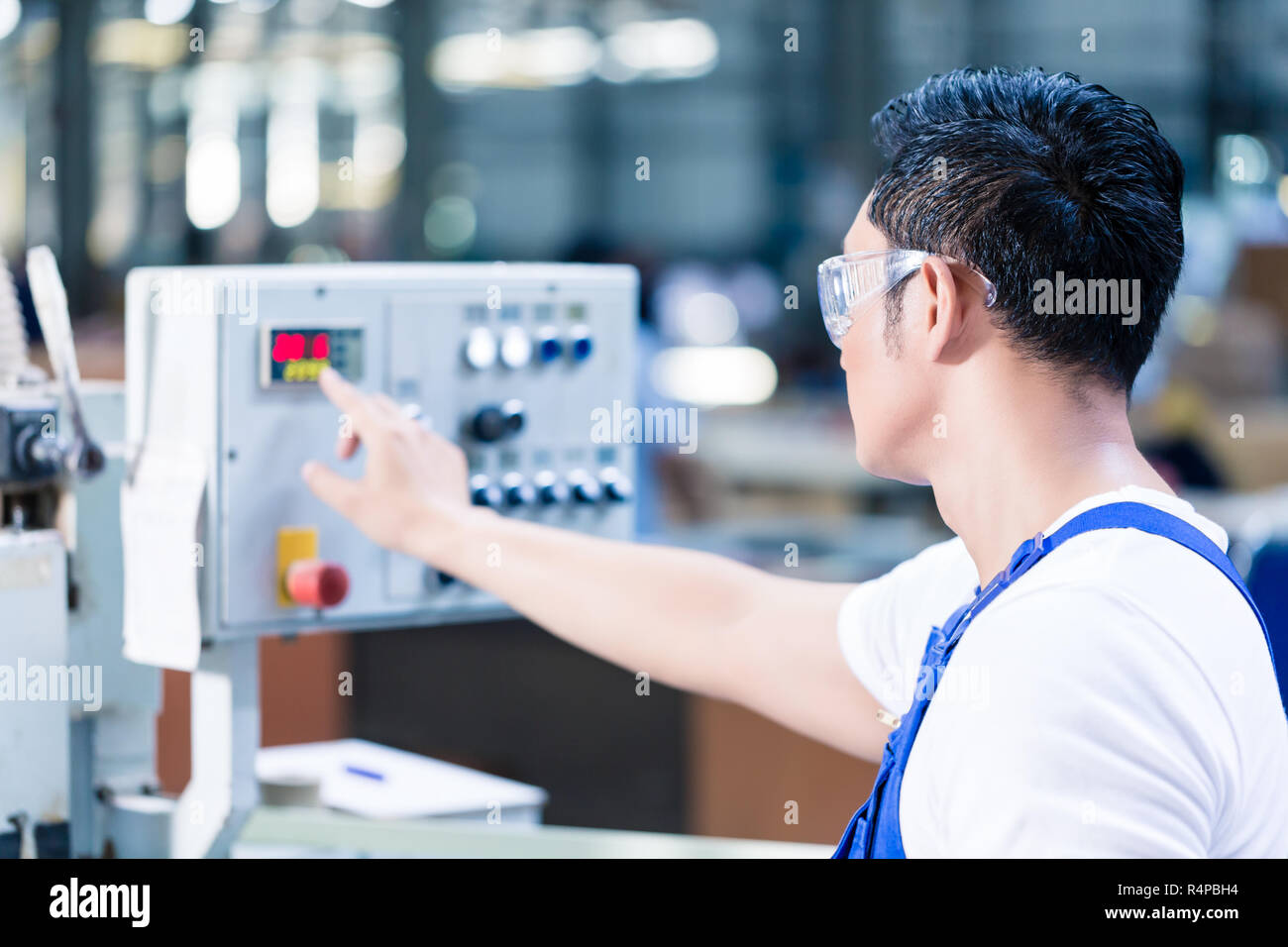 Worker pressing buttons on CNC machine in factory Stock Photo - Alamy