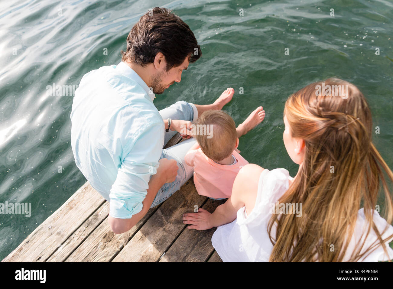 Family sitting on water hanging feet in the pond Stock Photo - Alamy