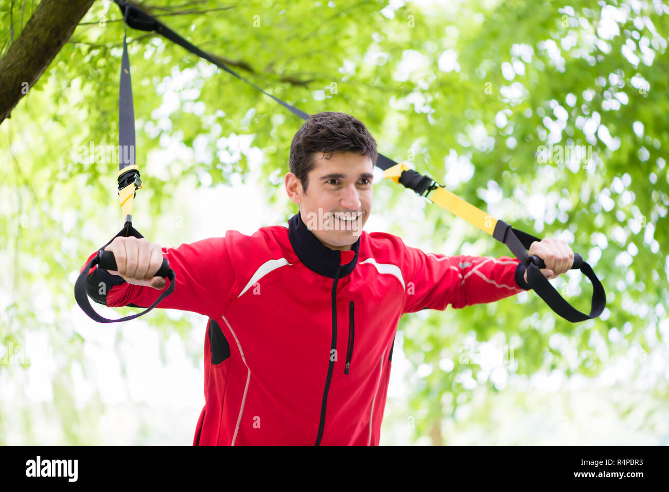 Man doing fitness sling training outdoors Stock Photo - Alamy