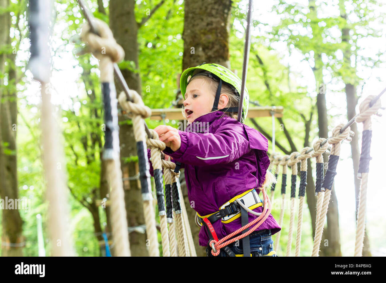 Girl climbing in high rope course Stock Photo - Alamy