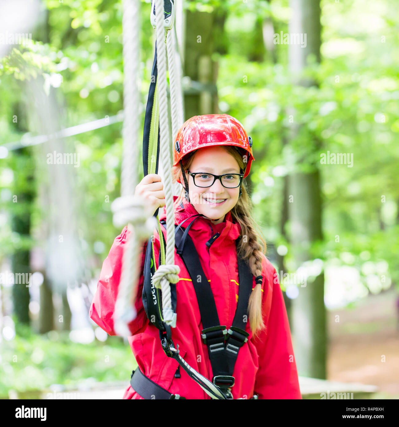 Girl roping up in high rope course Stock Photo - Alamy