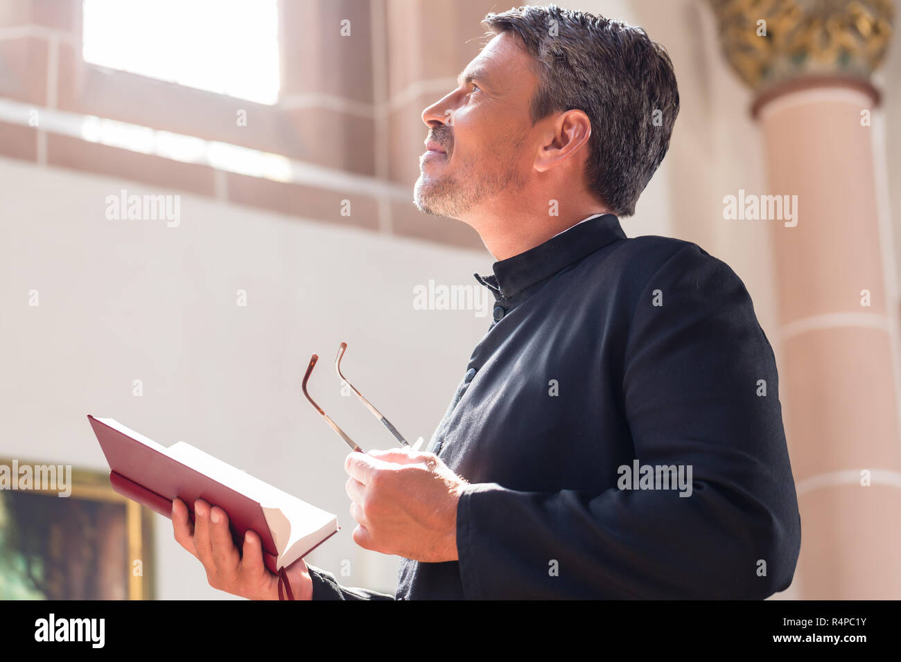 Catholic priest reading bible in church Stock Photo - Alamy