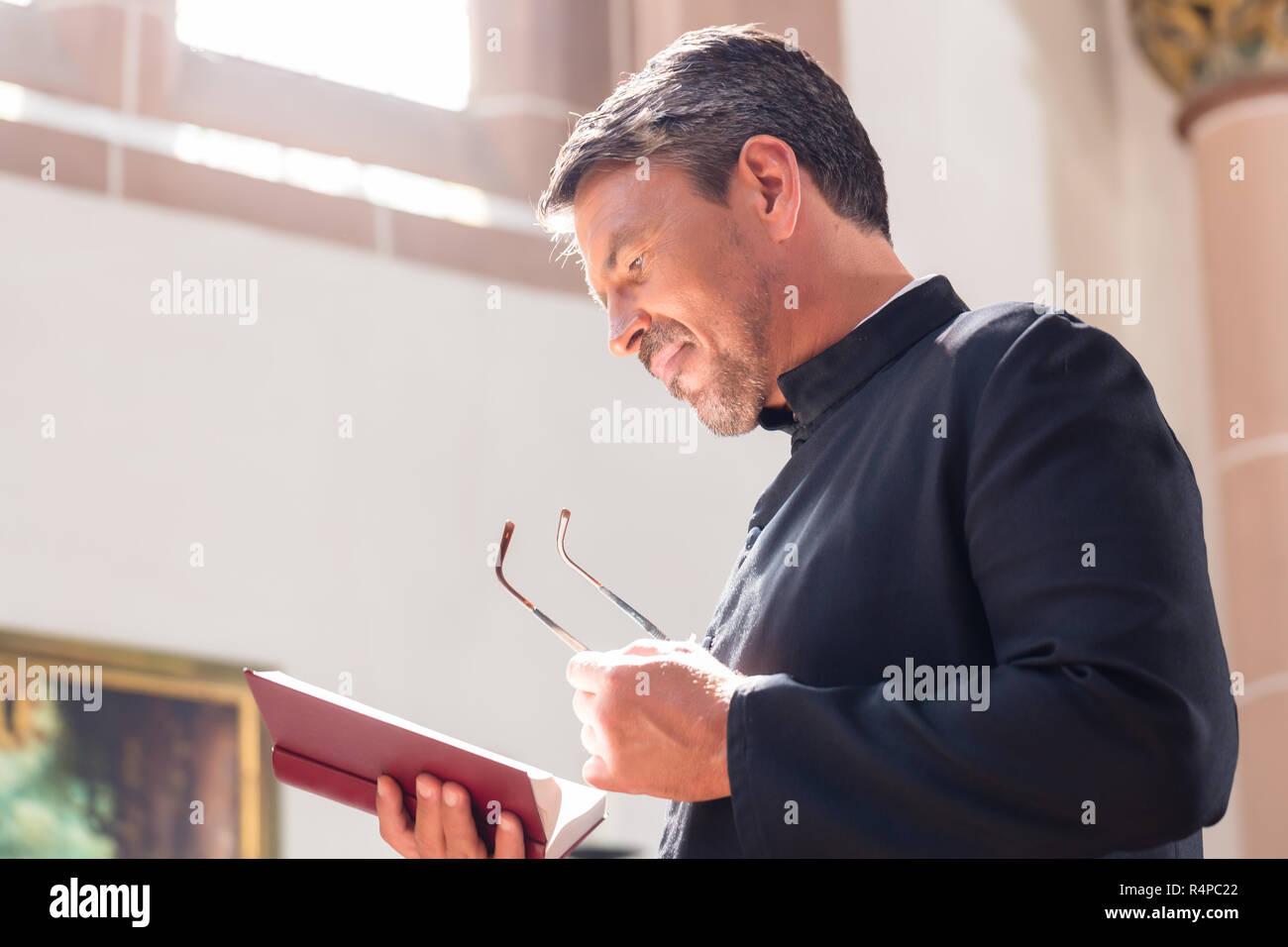 Catholic priest reading bible in church Stock Photo - Alamy