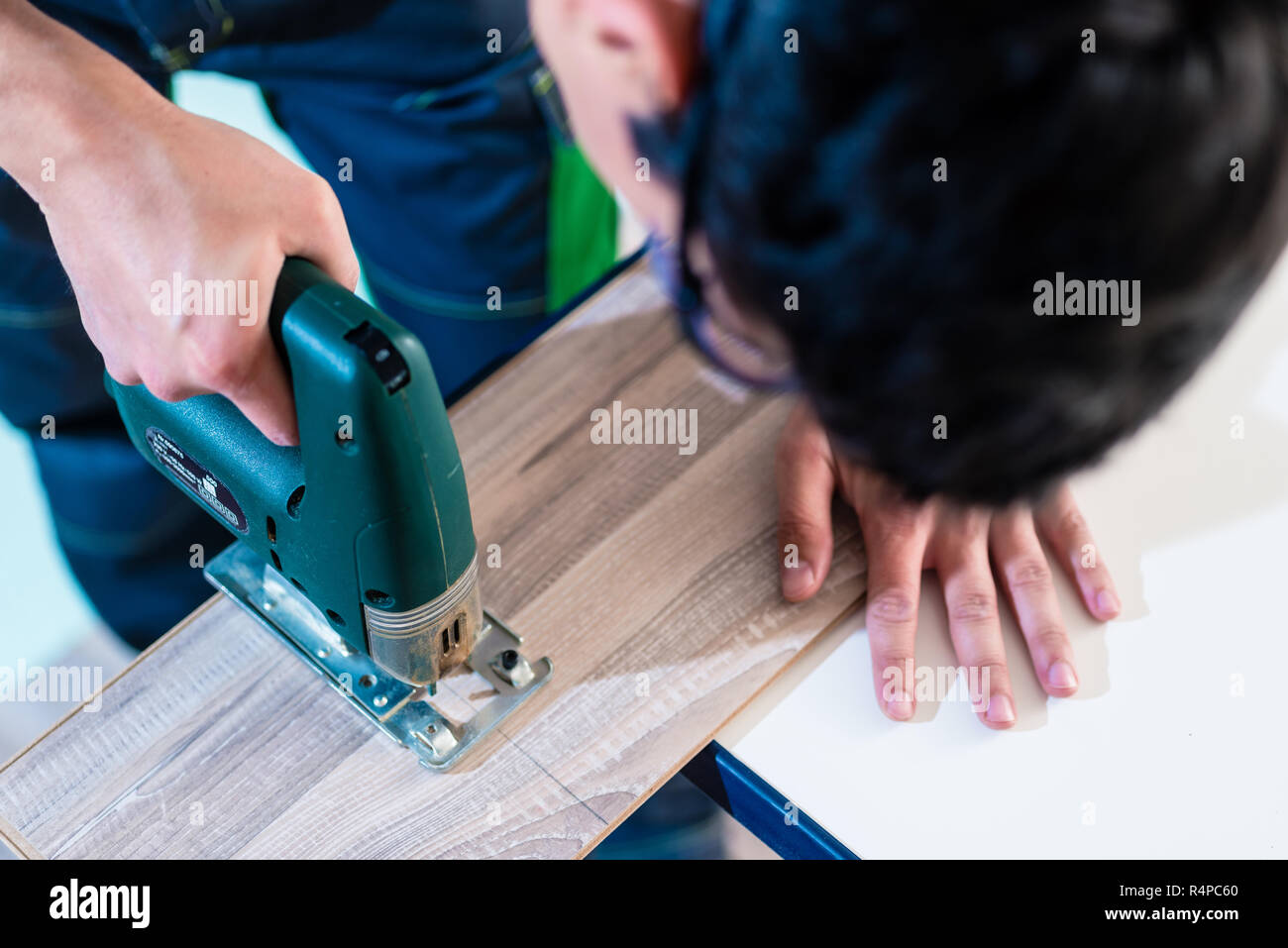 DIY worker cutting wooden panel with jig saw Stock Photo - Alamy