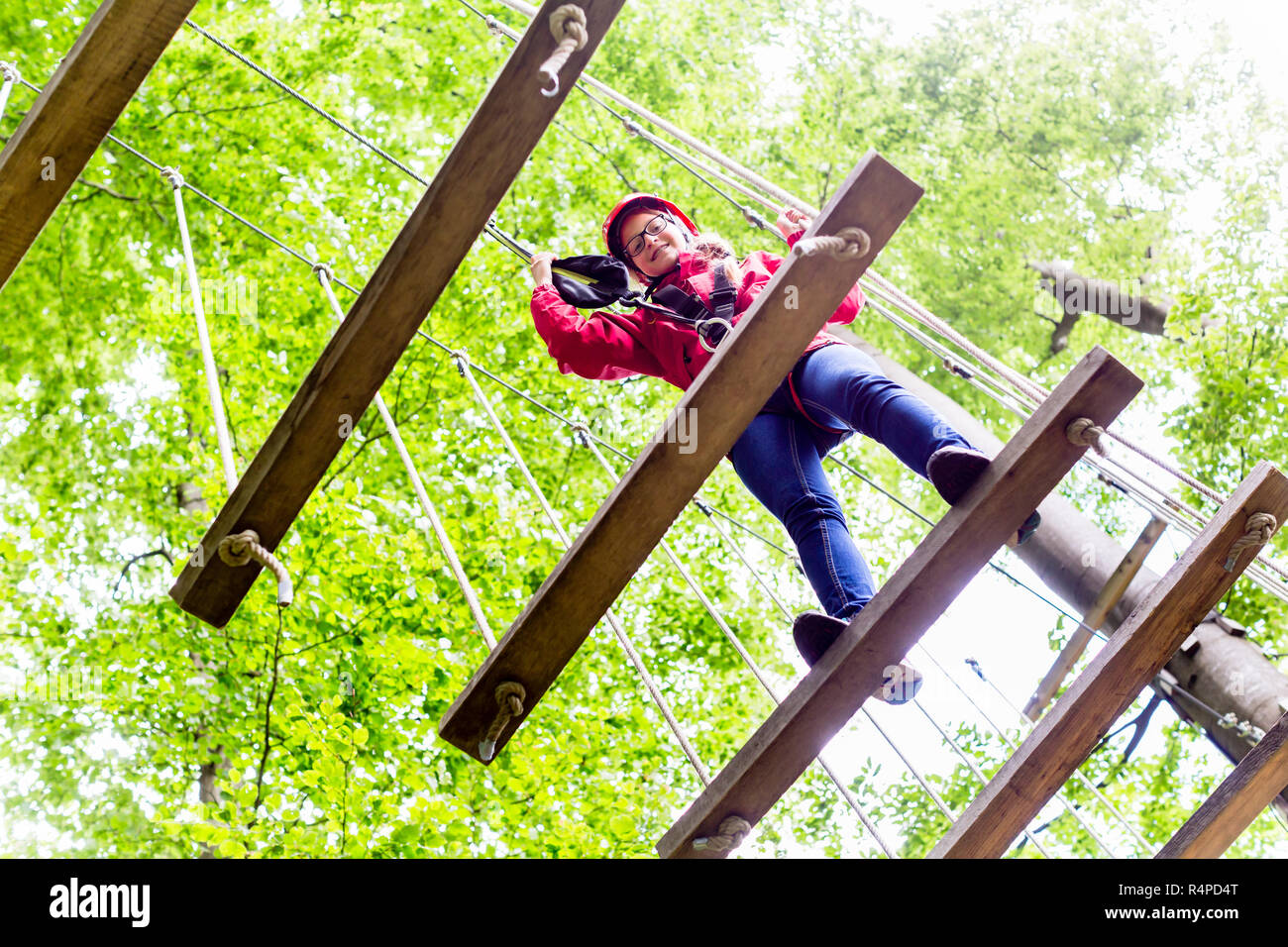 Kid walking on rope bridge in climbing course Stock Photo - Alamy