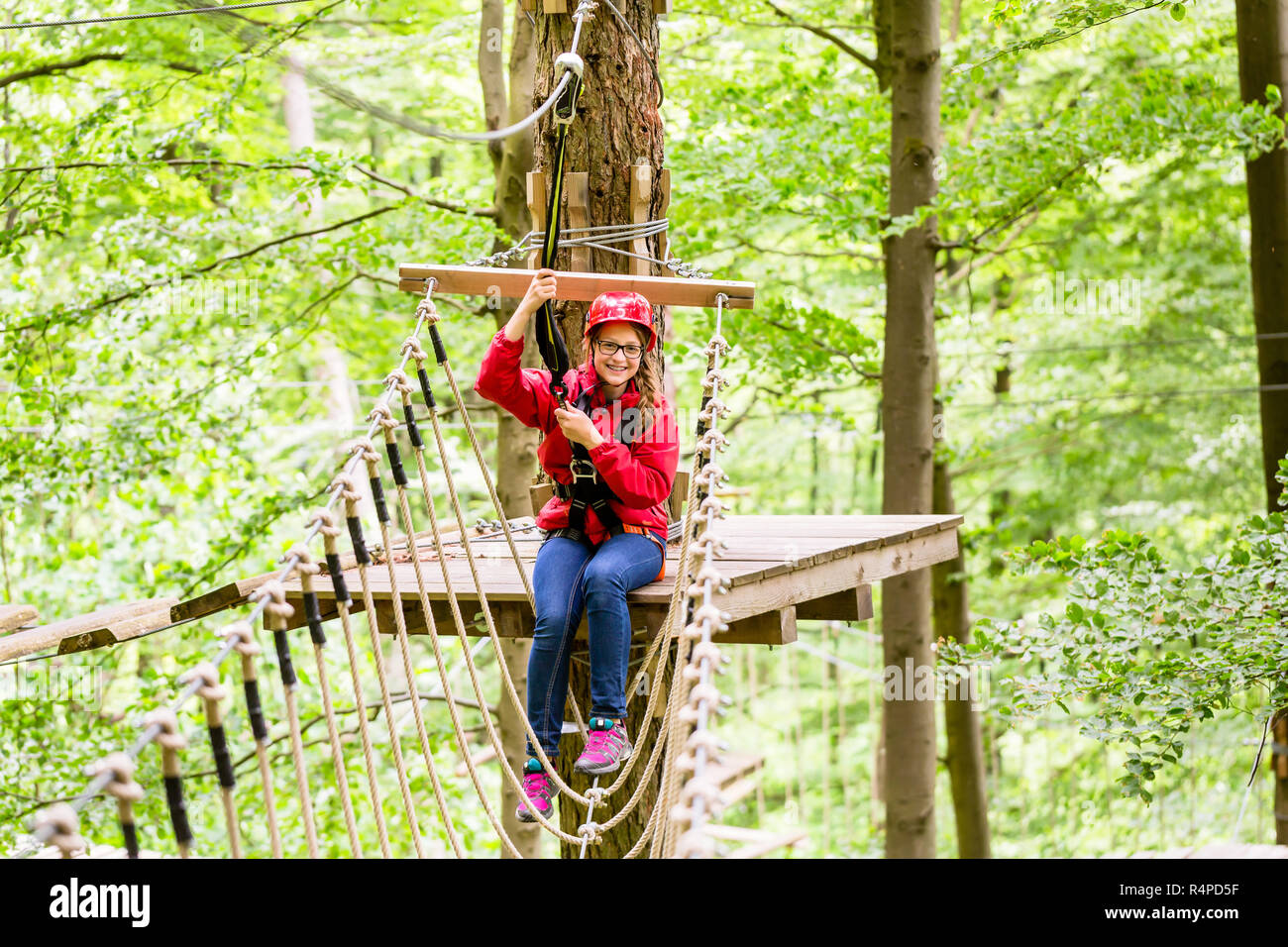 Child reaching platform climbing in high rope course Stock Photo - Alamy