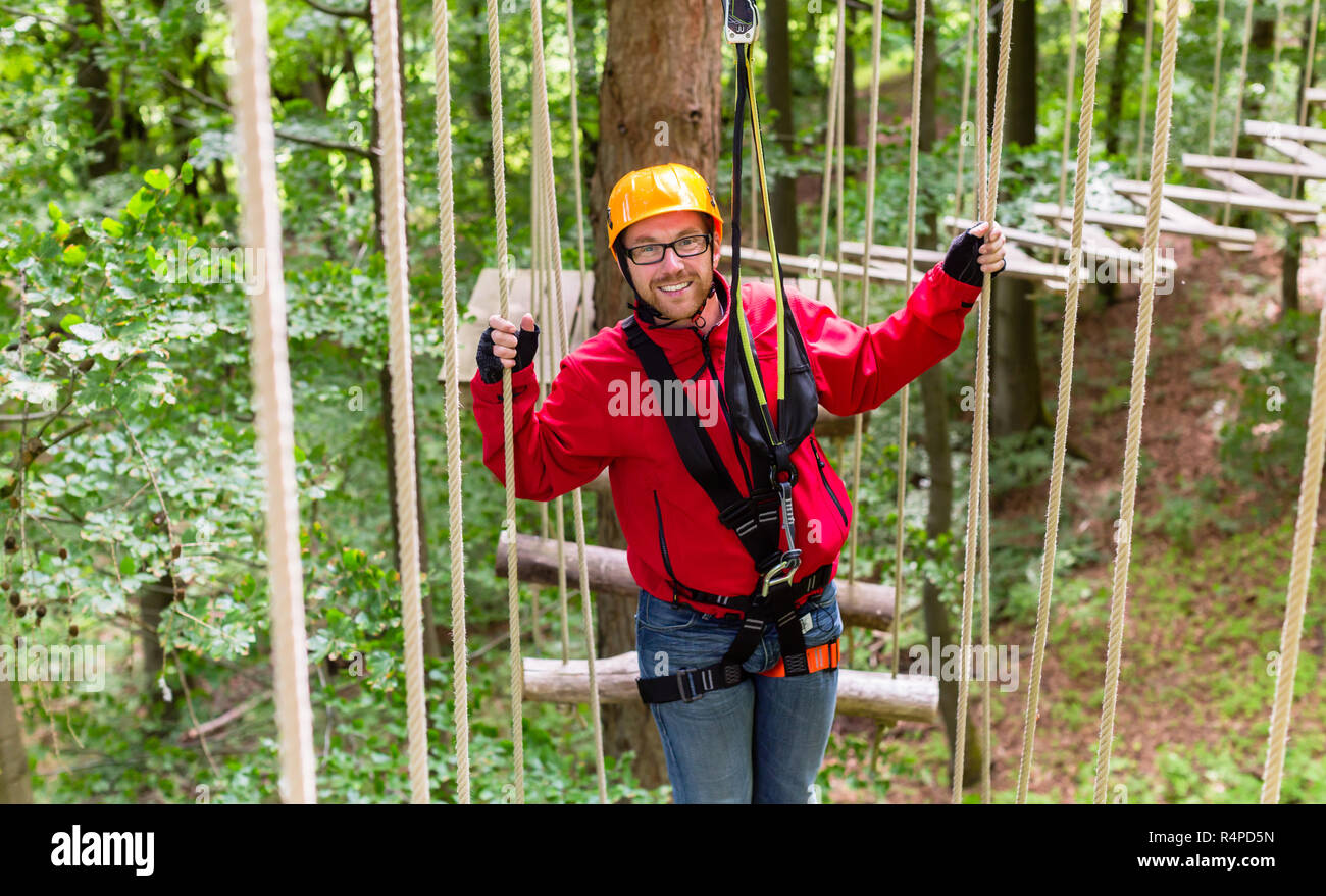 Man in high rope course climbing for sport Stock Photo - Alamy