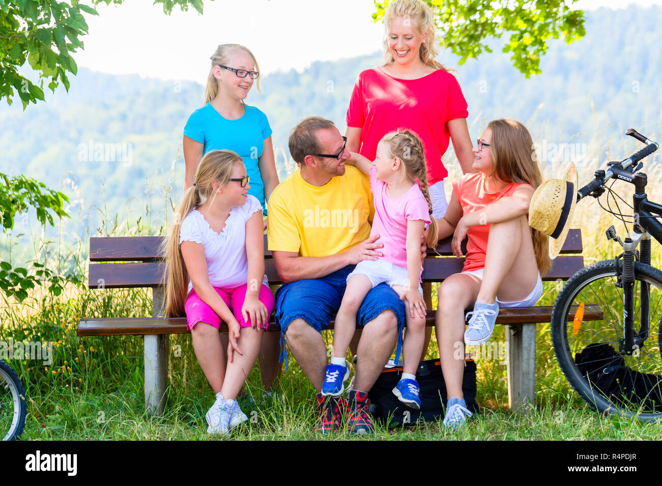 Family on tour with bikes having rest on bench Stock Photo - Alamy