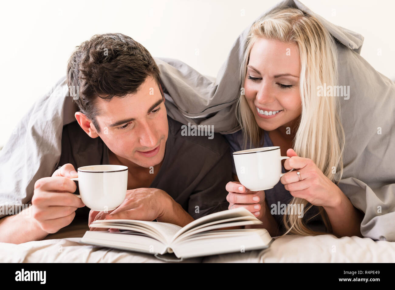 Young couple reading a book together in bed Stock Photo - Alamy