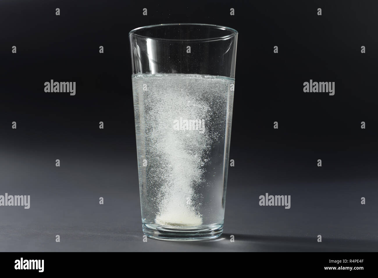 Soluble pill tablet in water with bubbles on black contrasty background ...