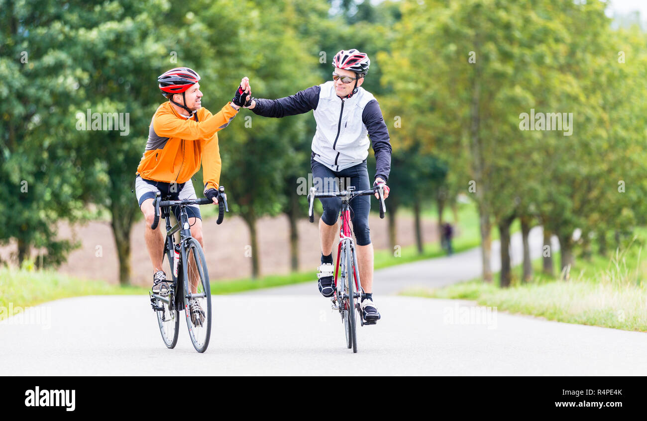 Racing cyclists after sport and giving high five Stock Photo - Alamy