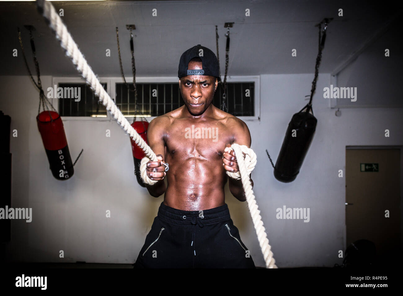 Portrait of young determined man waving battle ropes during high ...