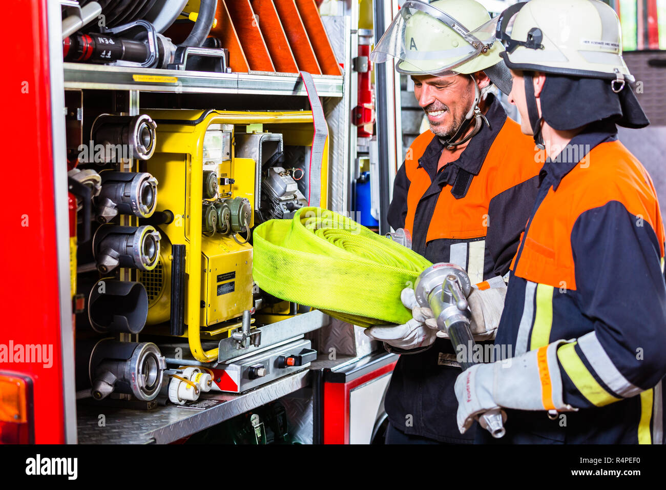Fire fighters loading hoses into operations vehicle Stock Photo - Alamy