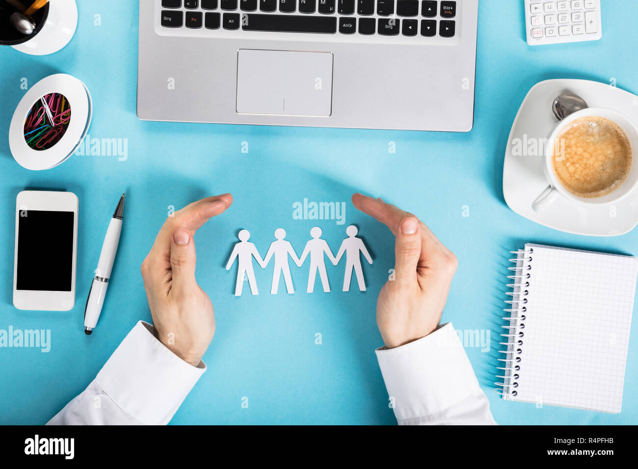 Businessman Protecting The Paper Cut Out Human Figure Stock Photo - Alamy