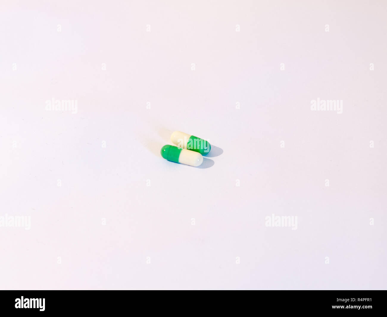 two basic generic pills on a white background white and green drugs ...
