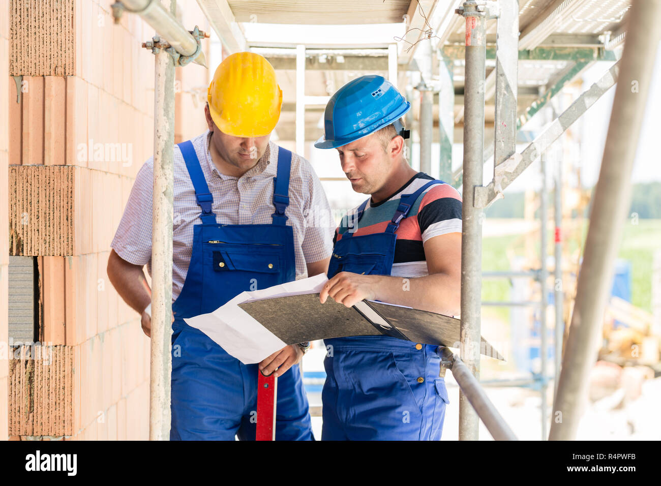 construction workers on site having discussion in scaffold with plans ...