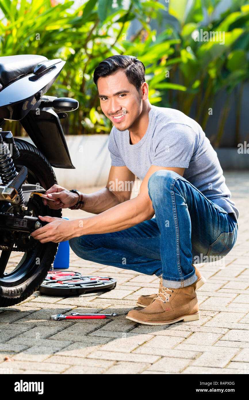 Asian man working on his motor scooter Stock Photo - Alamy