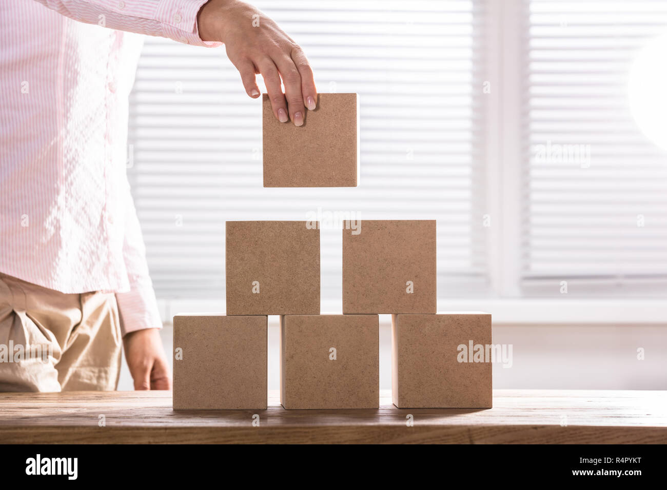 Woman Placing Block On Desk Stock Photo - Alamy
