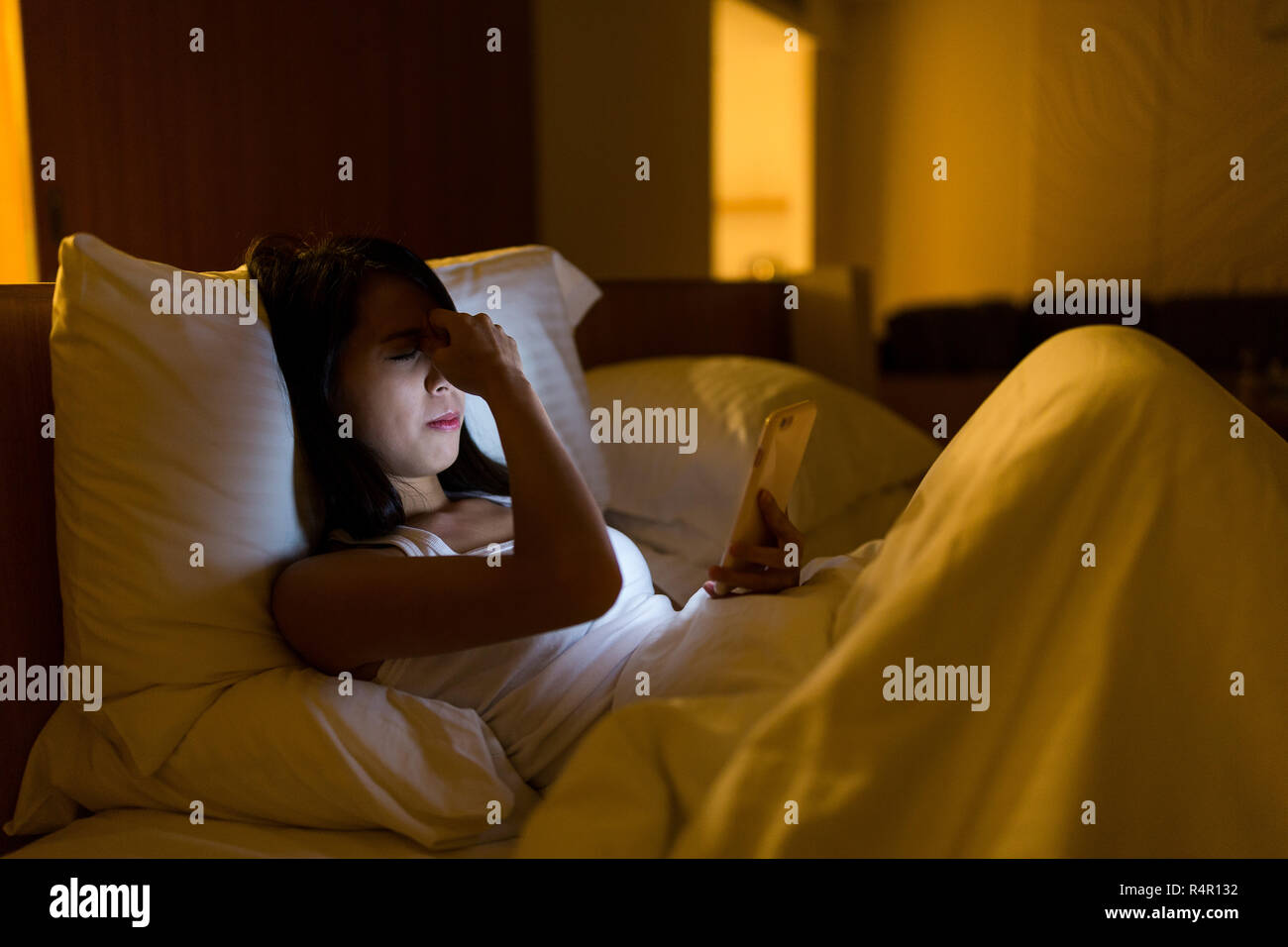 Woman feeling headache and using cellphone Stock Photo - Alamy