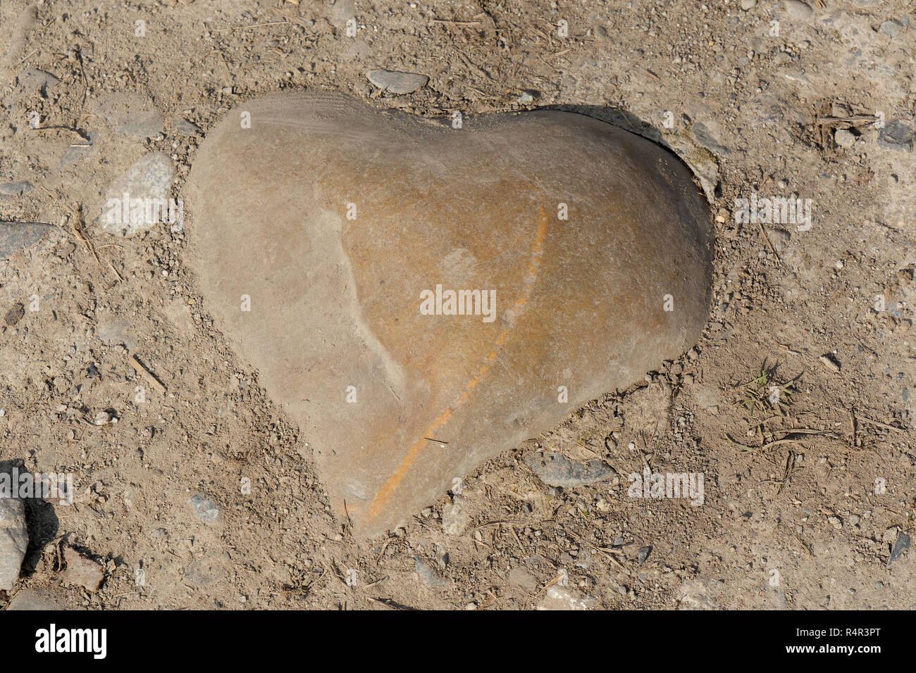 Stone in the shape of a heart in the ground Stock Photo - Alamy