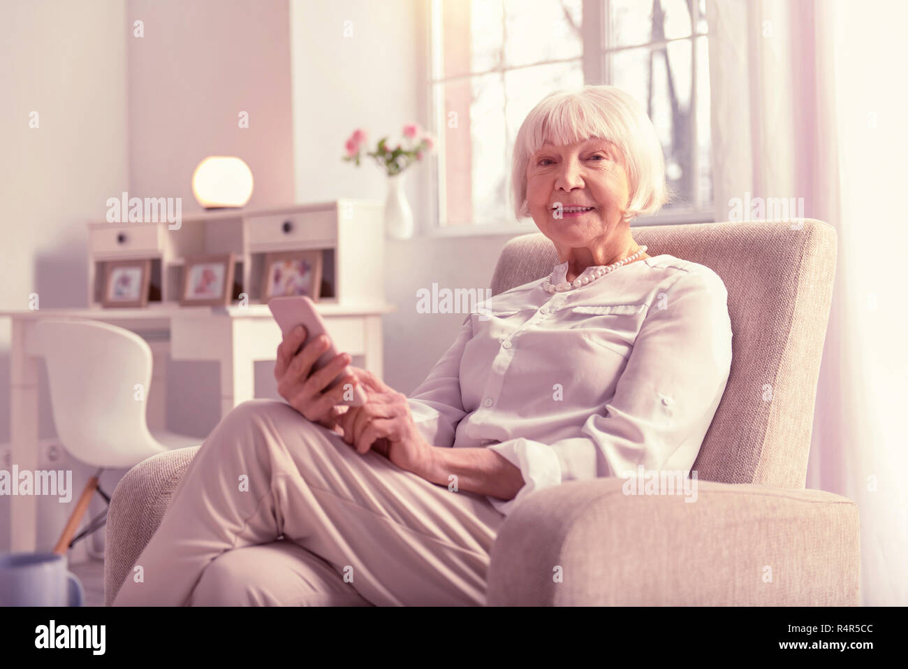 Positive grey-haired mature lady checking her phone Stock Photo - Alamy