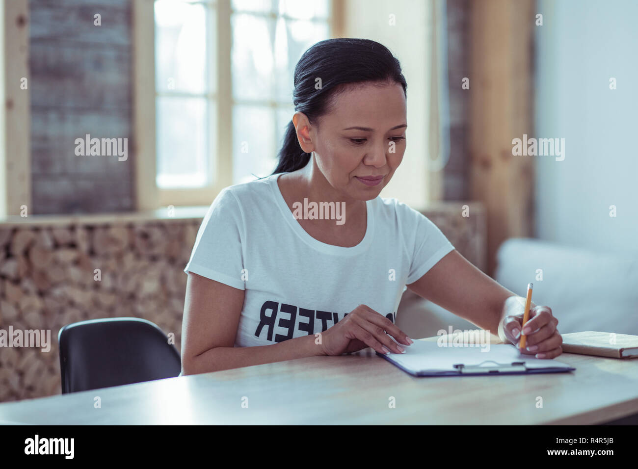 Concentrated young brunette female person making notes Stock Photo - Alamy