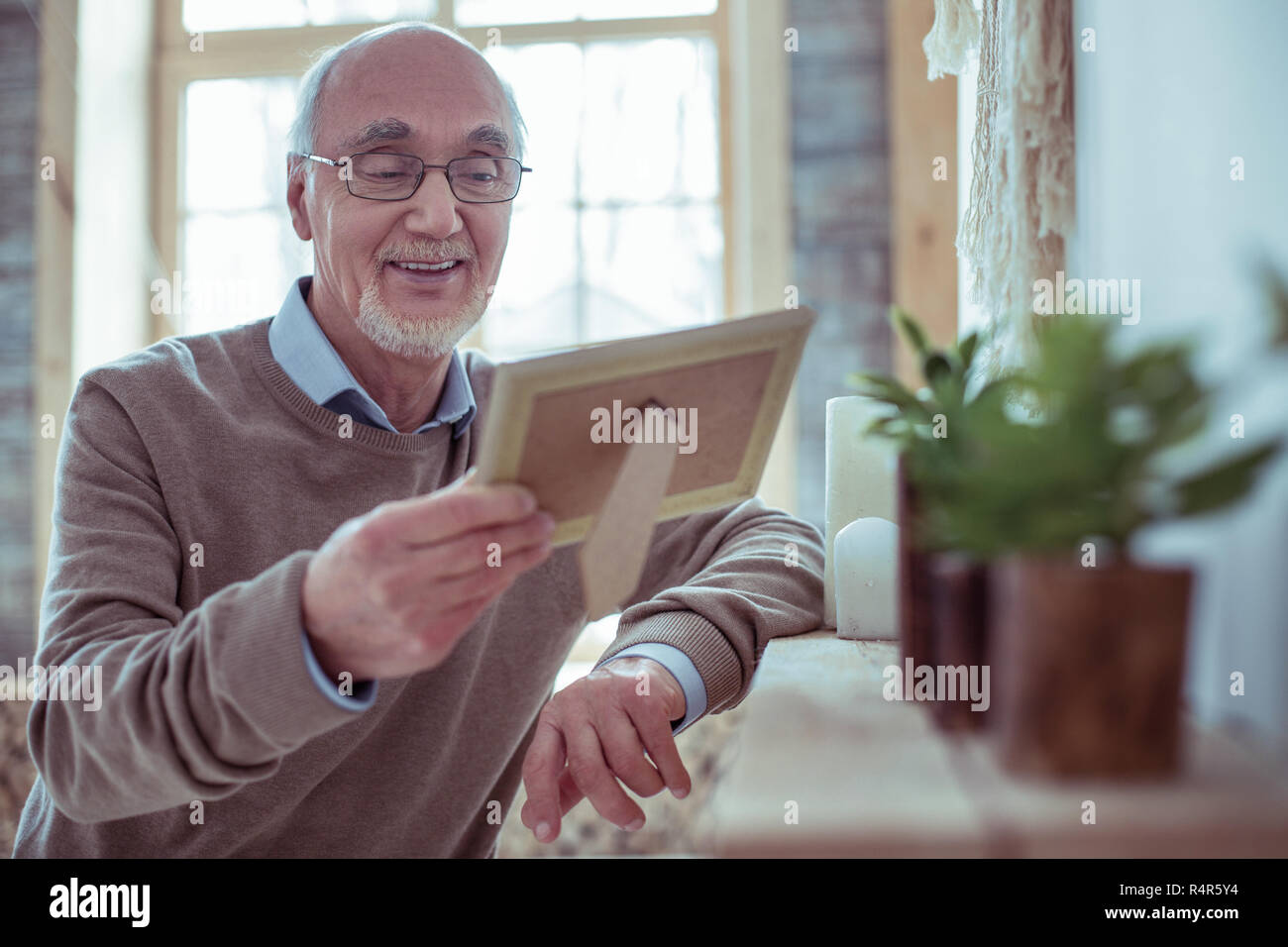 Positive delighted retirement looking at family photo Stock Photo - Alamy
