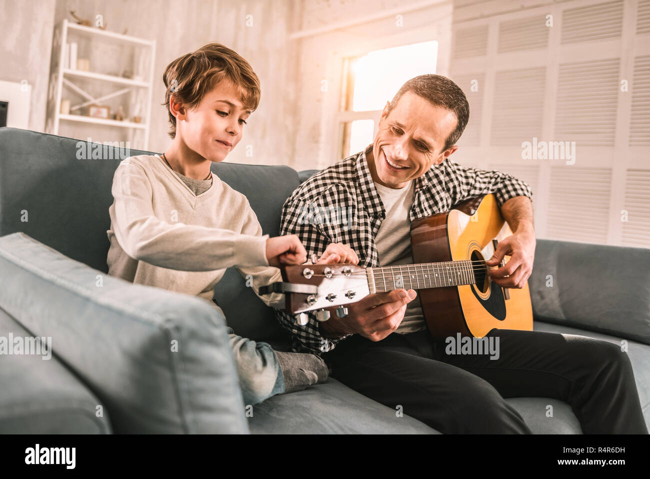 Loving son asking for help from his dad on a music class Stock Photo ...