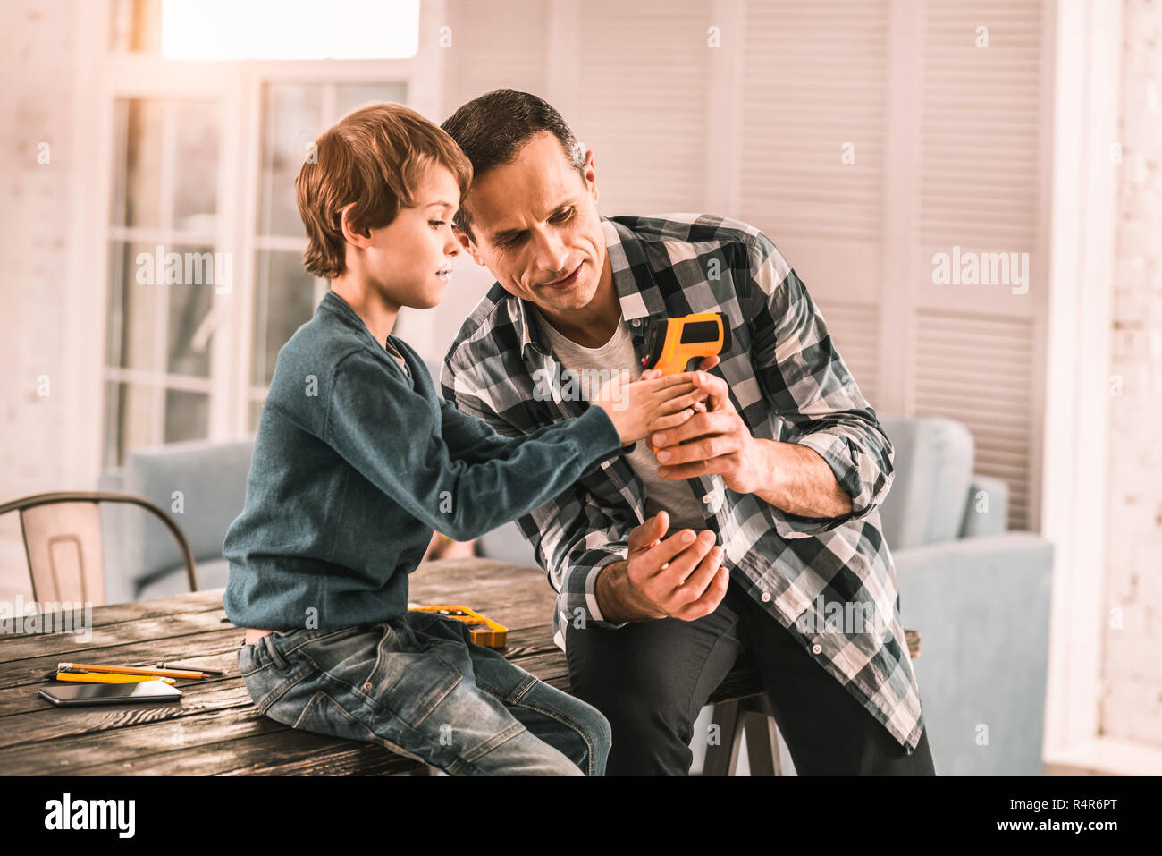 Interested father showing his son some cool functions of his tool Stock ...