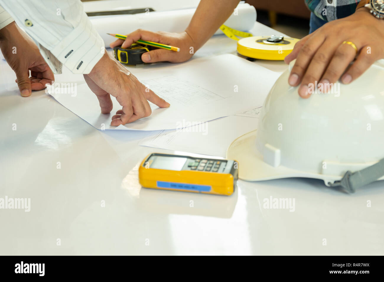 Asian architectuer working on plan hands pointing at bluepring sketch ...