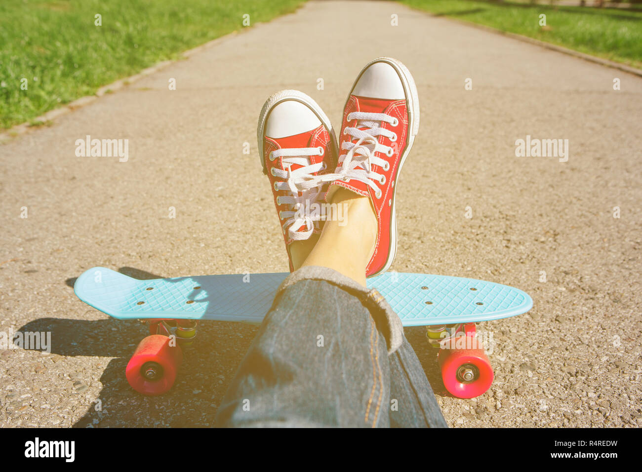 Close up of feet of a girl in red sneakers rides on blue plastic penny ...