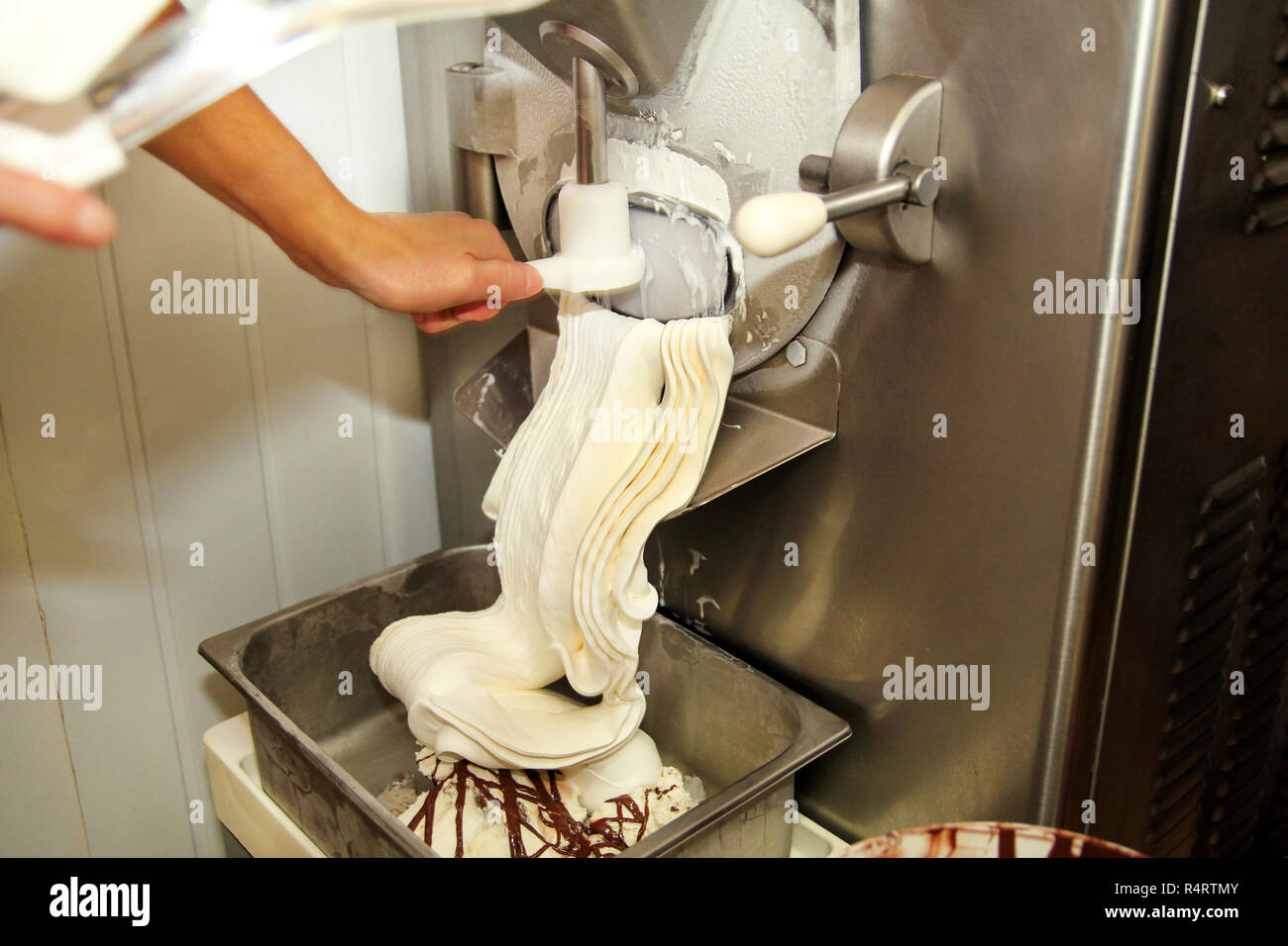 Female worker is working on ice cream maker machine. Producing vanilla ...