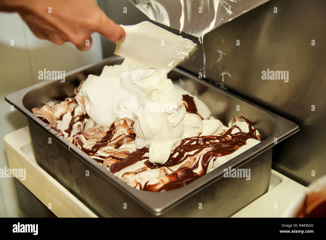 Female worker is working on ice cream maker machine. Producing vanilla ...