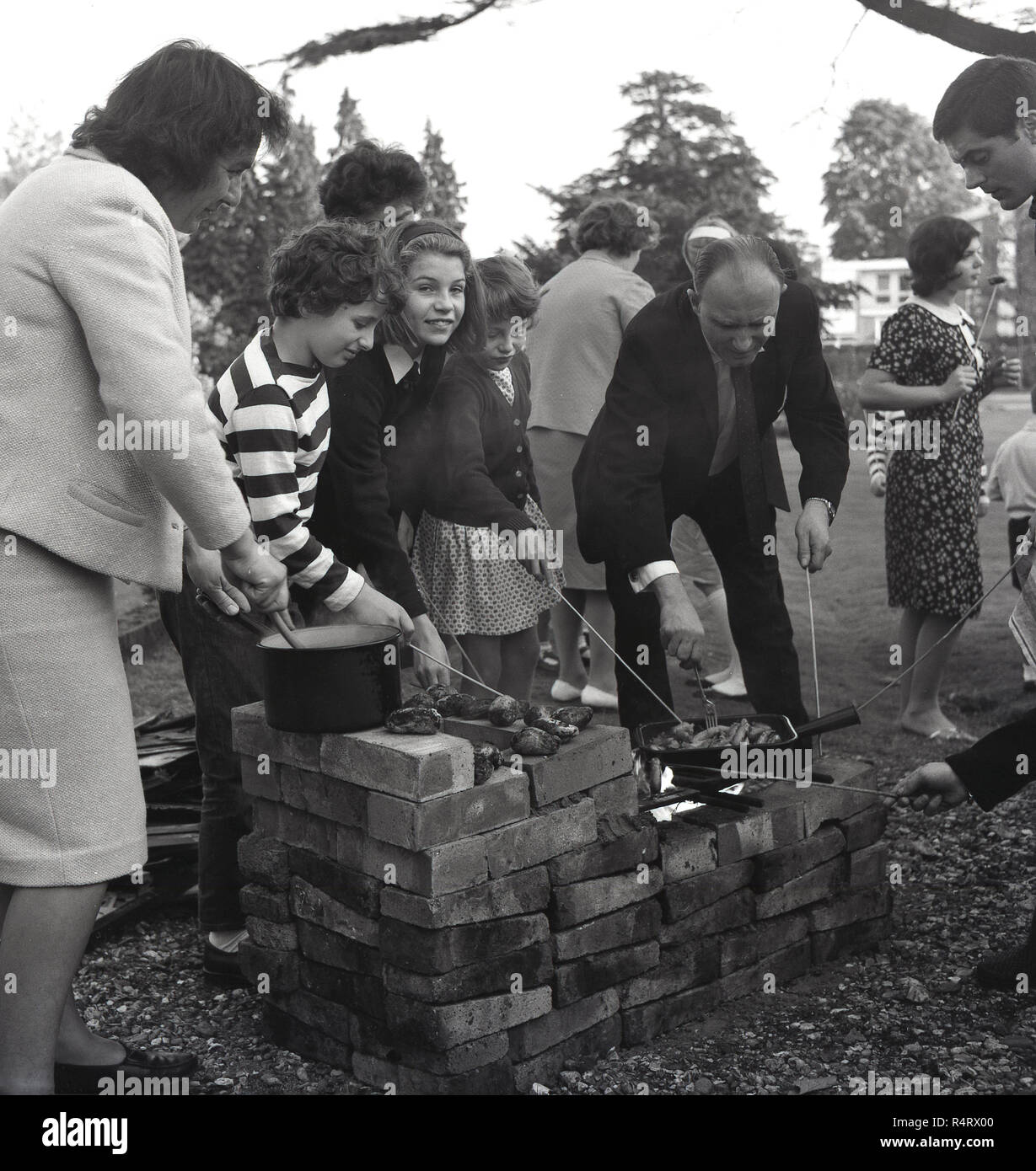 1965, historical, children and adults outside at a brick barbeque ...