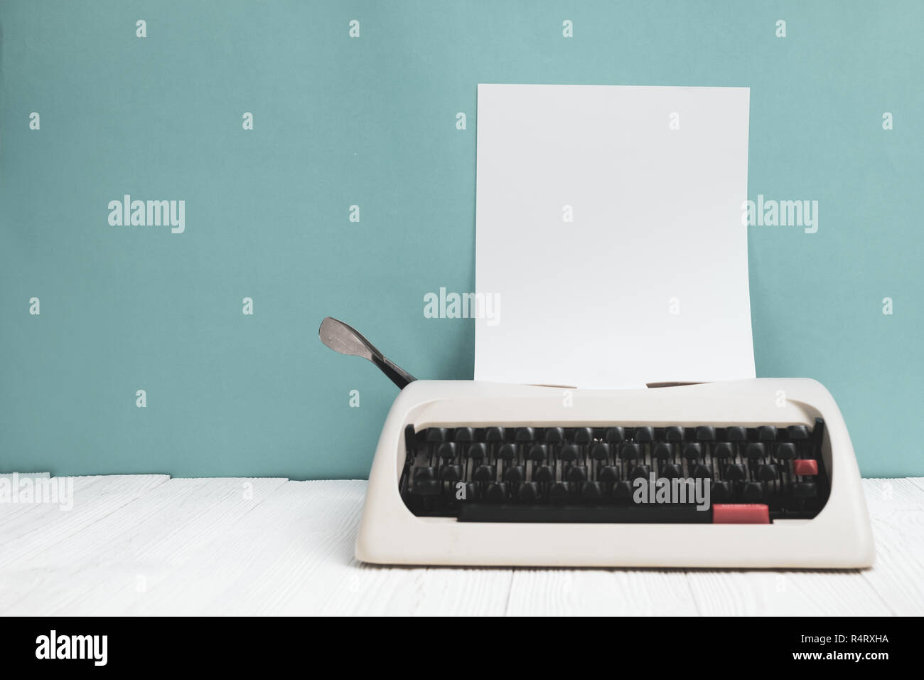 Retro typewriter with blank paper sheet on white wood table front blue ...