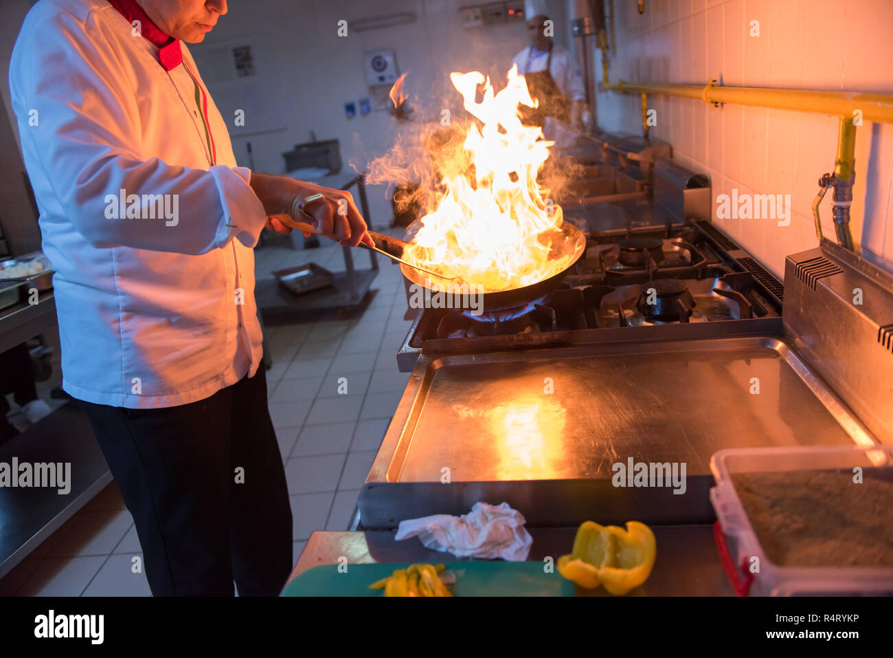 Chef cooking and doing flambe on food in restaurant kitchen Stock Photo ...
