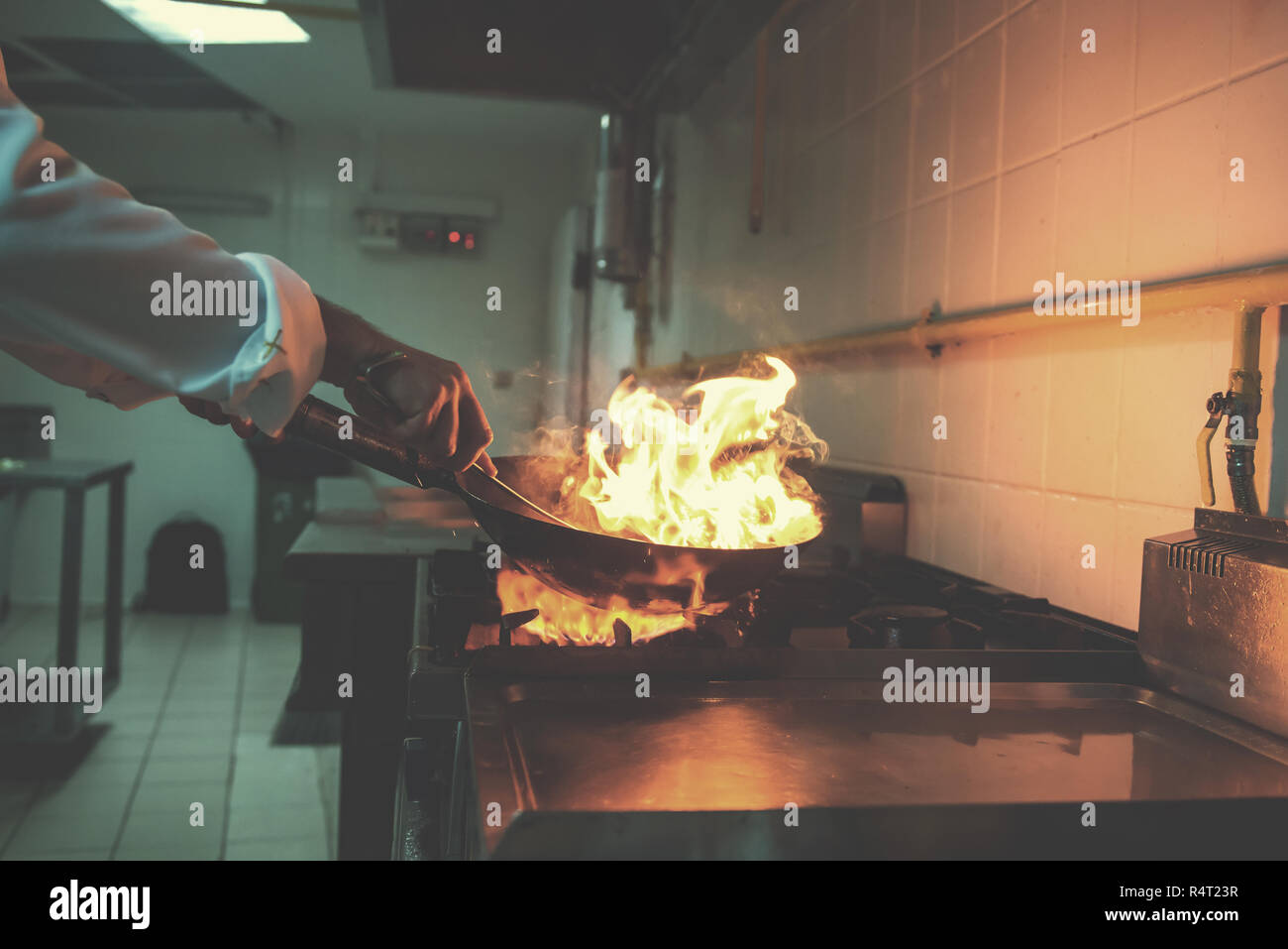 Chef cooking and doing flambe on food in restaurant kitchen Stock Photo ...