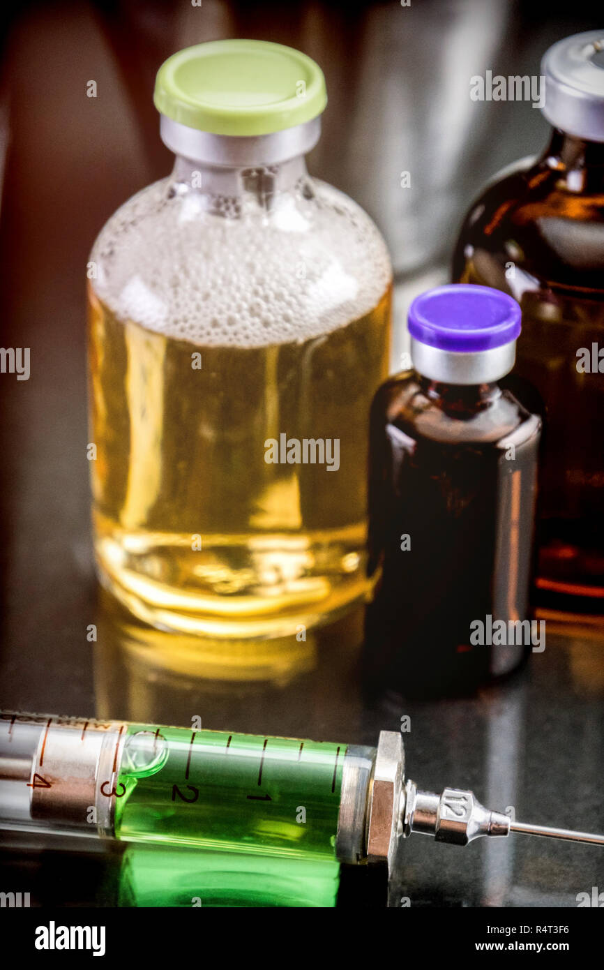 Vials of different size next to syringe of metal in a laboratory ...