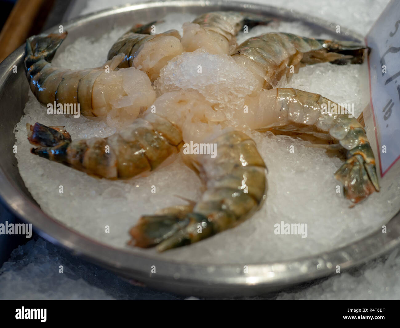 Group of raw shrimp sitting in circular bowl filled with ice at a ...