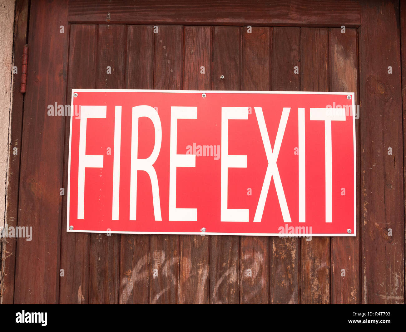 a big red and white sign outside on a fence saying fire exit wood metal ...