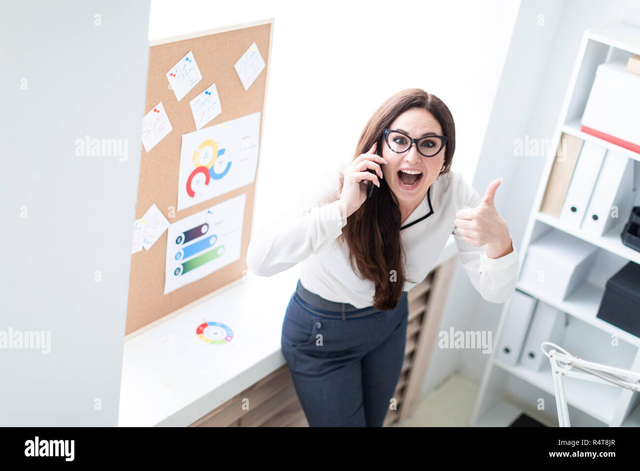 Young girl talking on the phone and shows a sign class Stock Photo - Alamy